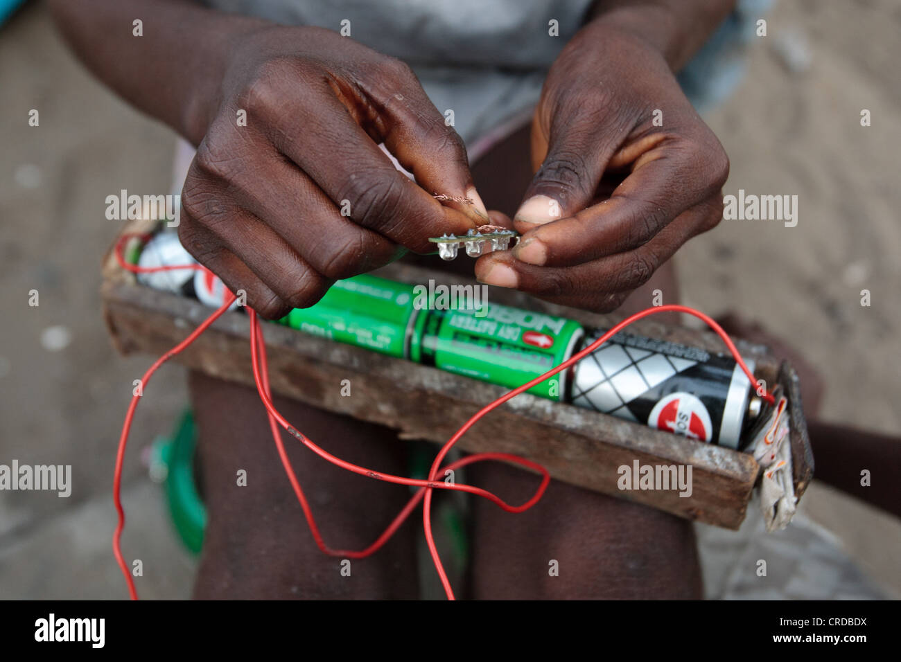 A boy plays with batteries and a small light in the West Point slum in ...