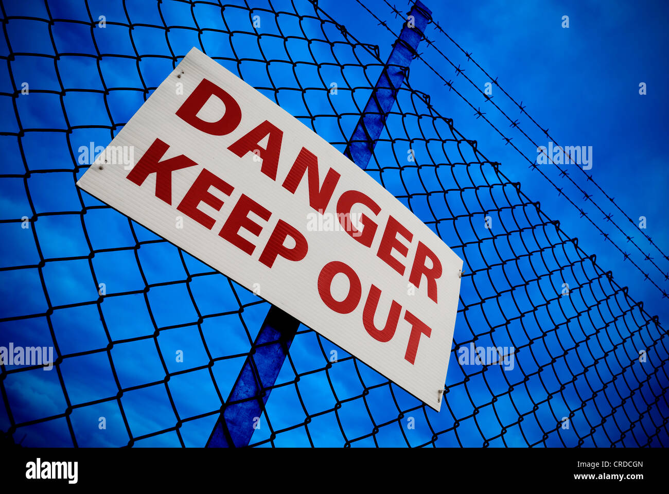 Danger Keep Out sign on a chain link fence topped with barbed wire ...