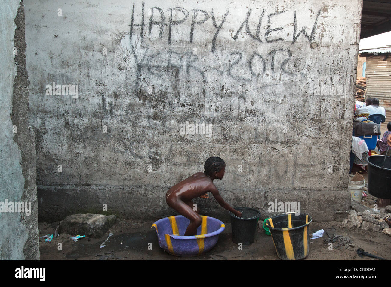 A girl bathes in a plastic container in the West Point slum in Monrovia ...