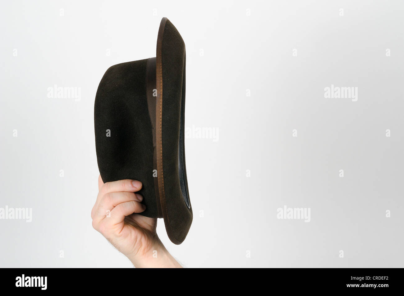 Hand holding a brown bowler hat Stock Photo - Alamy