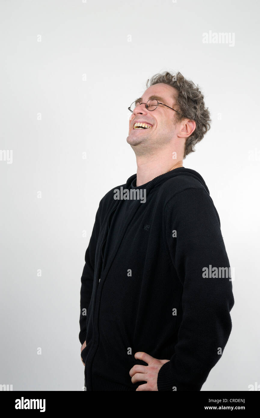 Young man with glasses laughing heartily, hands on hips Stock Photo - Alamy