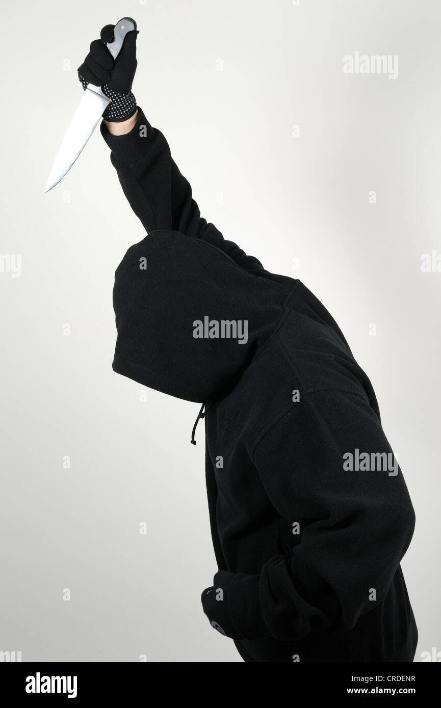 Man with a black hooded shirt and a raised knife Stock Photo - Alamy