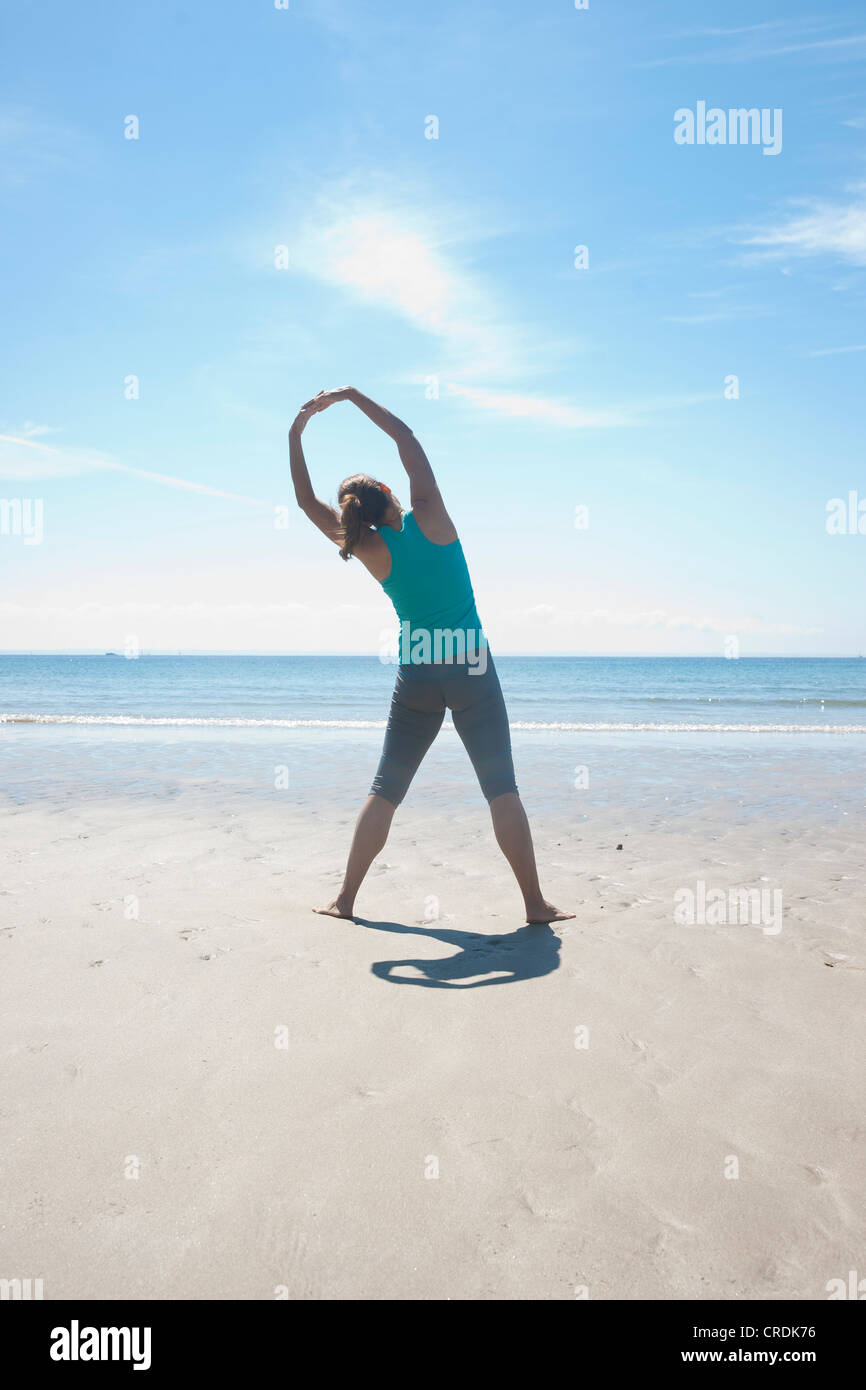 Woman doing stretching exercises, gymnastics on the beach, Camaret-sur ...
