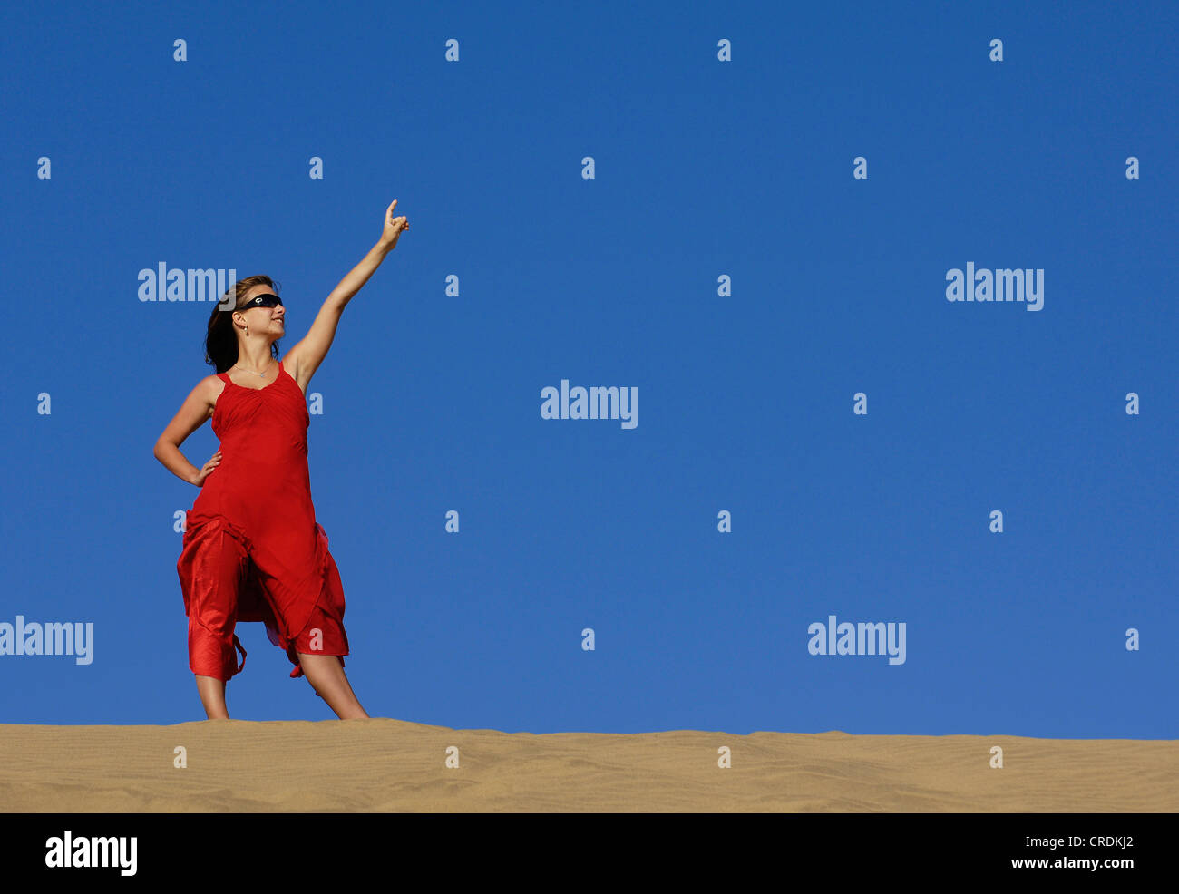 young woman standing on sand, pointing upwards Stock Photo - Alamy