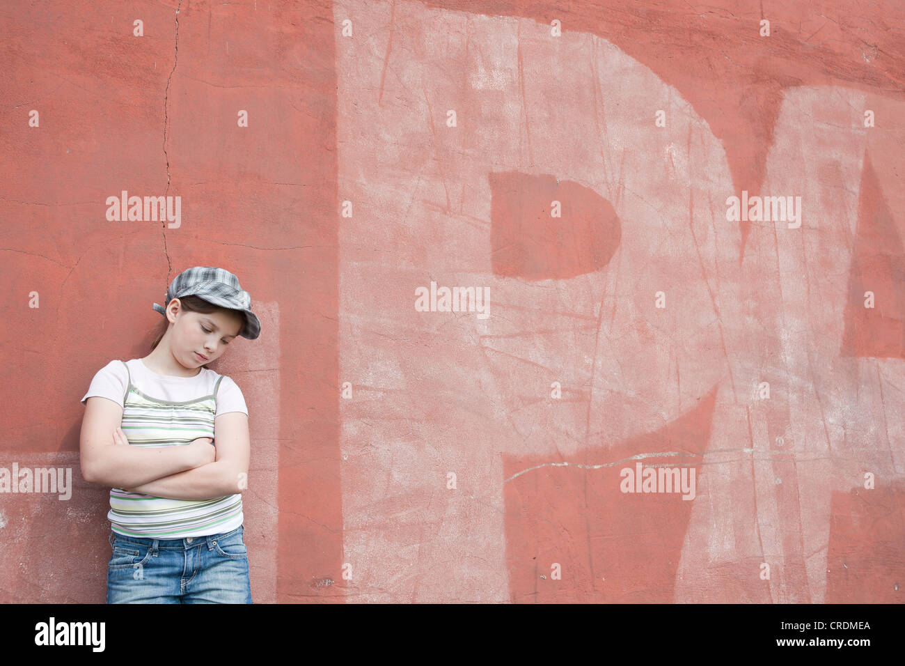 Sad young girl with hat standing in front of a graffiti wall Stock ...