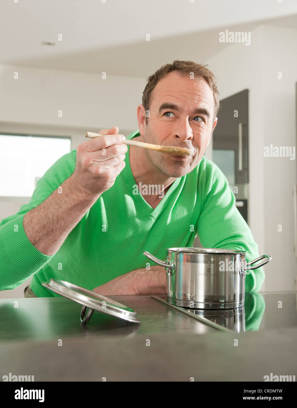 Man trying food from a cooking pot Stock Photo - Alamy