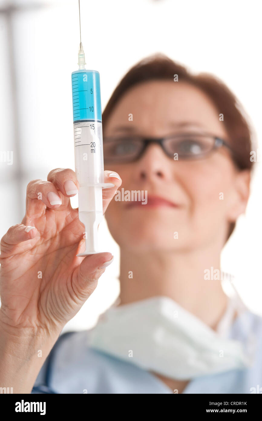 Female doctor controlling a syringe with blue liquid Stock Photo - Alamy