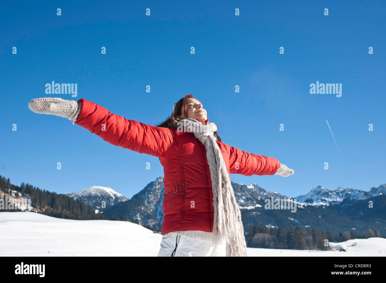 Woman standing in the snow with both arms raised sideways Stock Photo ...