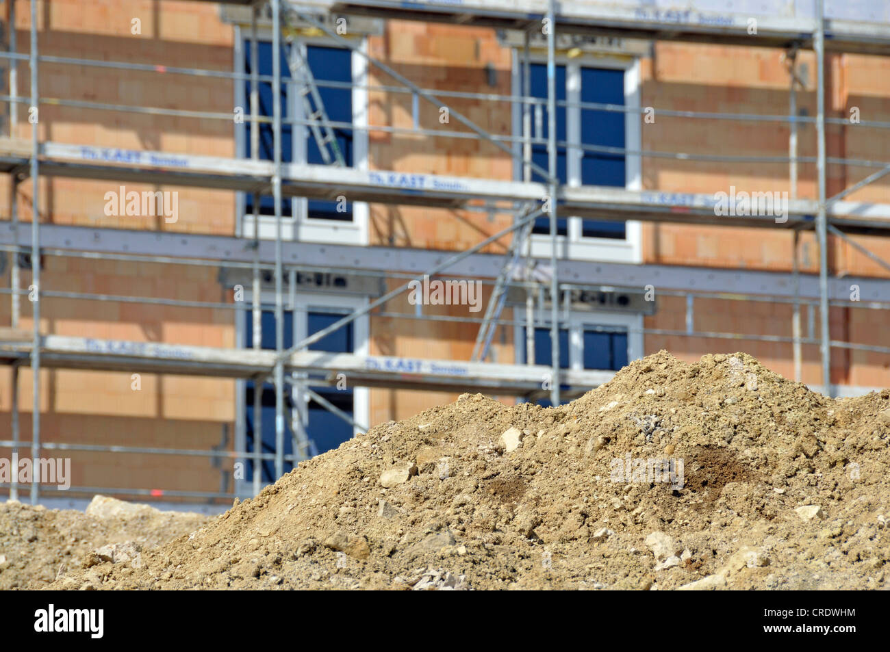 Earth bank in front of a scaffolded building under construction ...