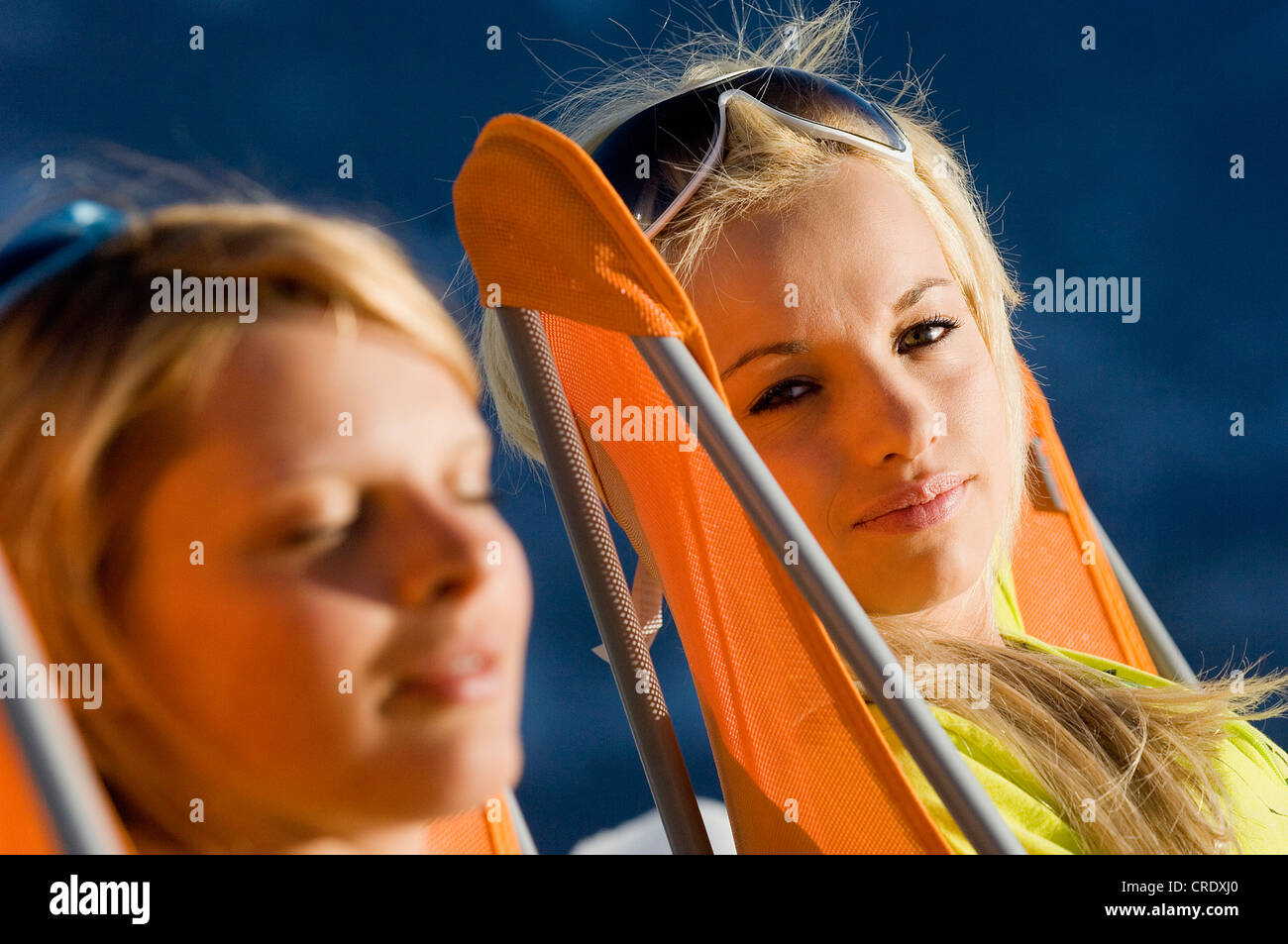 two young blond women sunbathing in the mountains, France, Alps Stock ...
