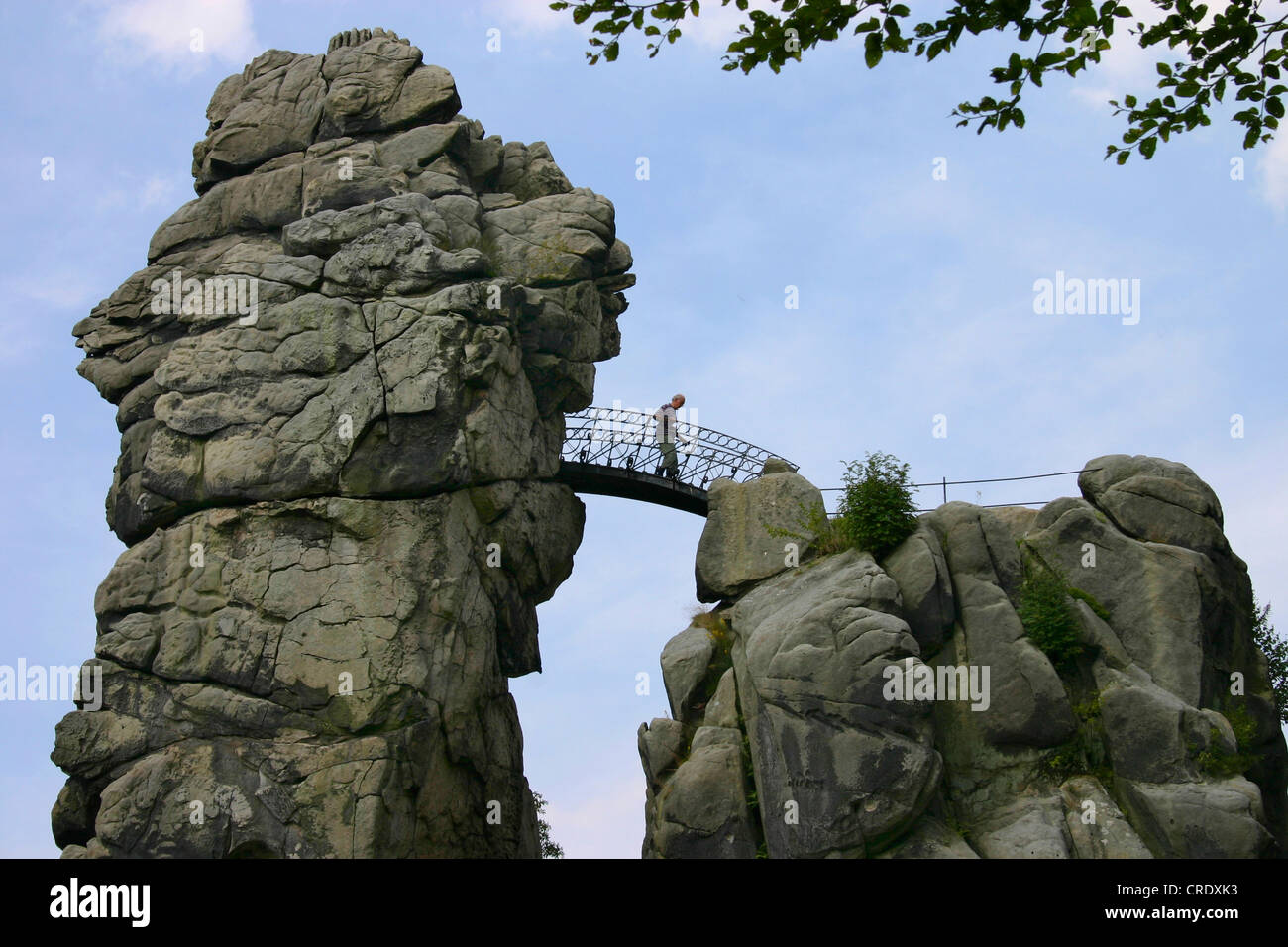 at rocks of the Externsteine, one person crosses the pedestrian bridge ...