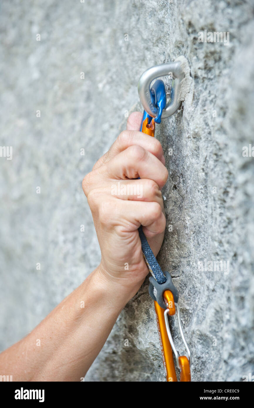 Hand of a mountaineer, climber, fastening a draw on a hook, rock, rock ...