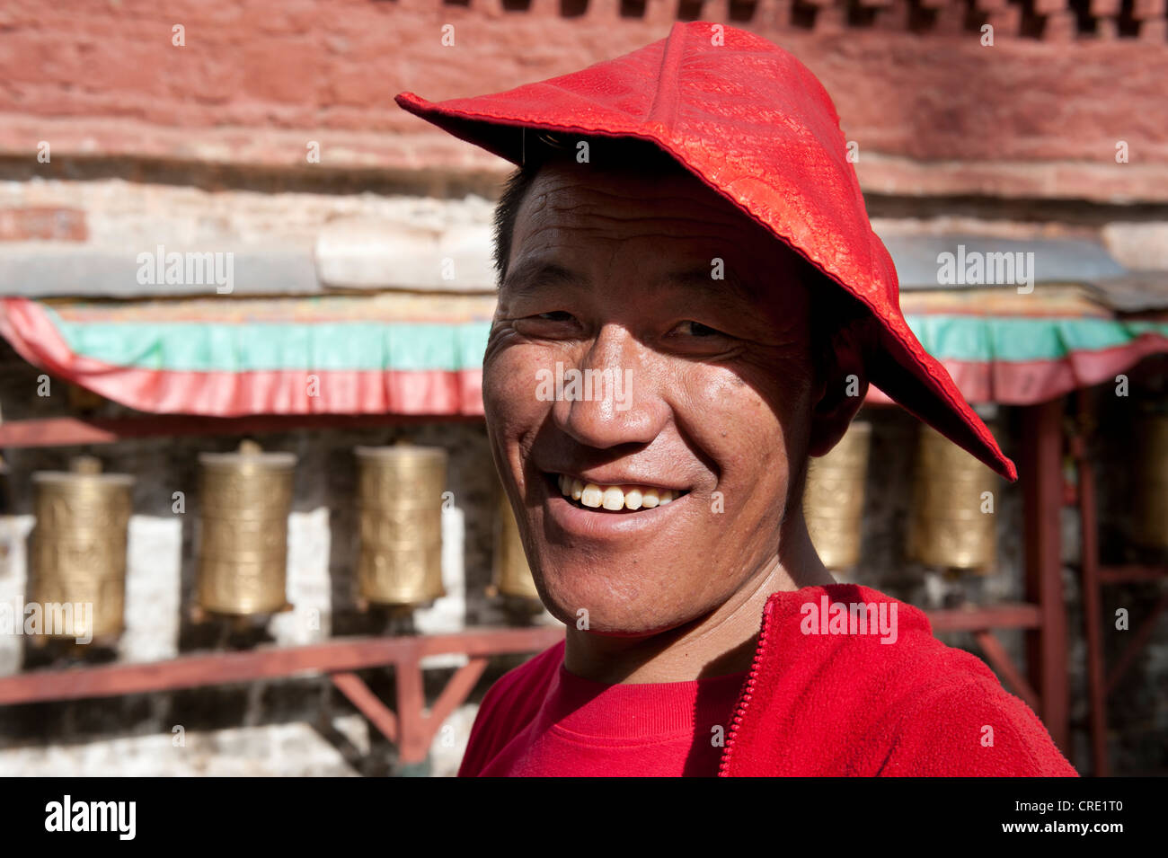 Tibetan Buddhism, monk wearing a red visor cap smiling, prayer wheels ...