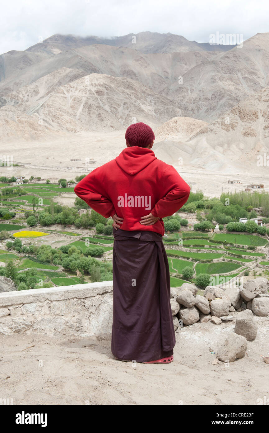 Tibetan Buddhism, monk standing up and looks into the green valley ...