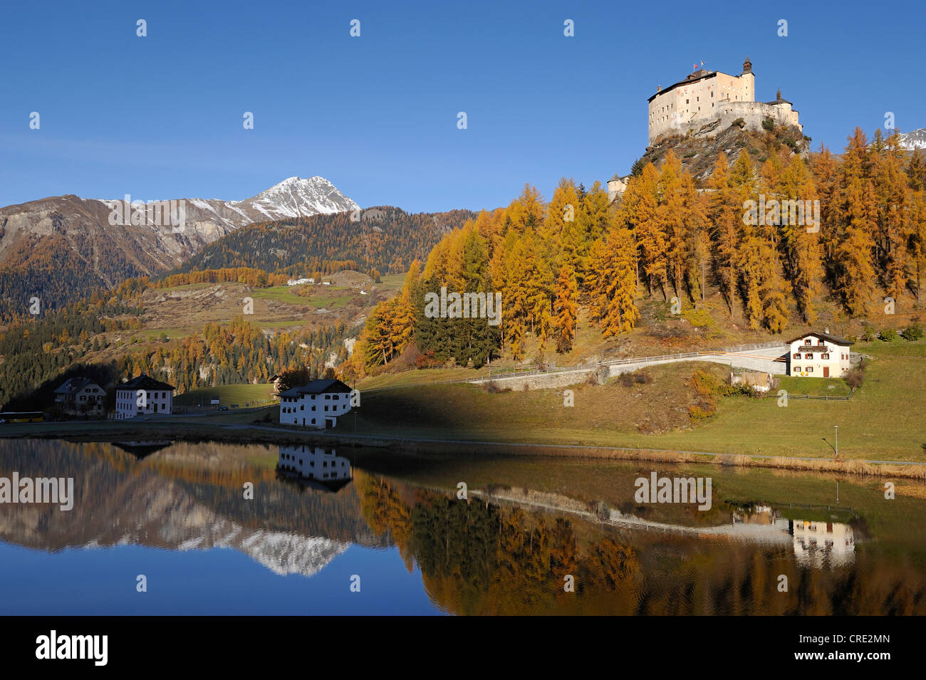 Schloss Tarasp Castle with Lake Tarasp in front of larch forest with ...