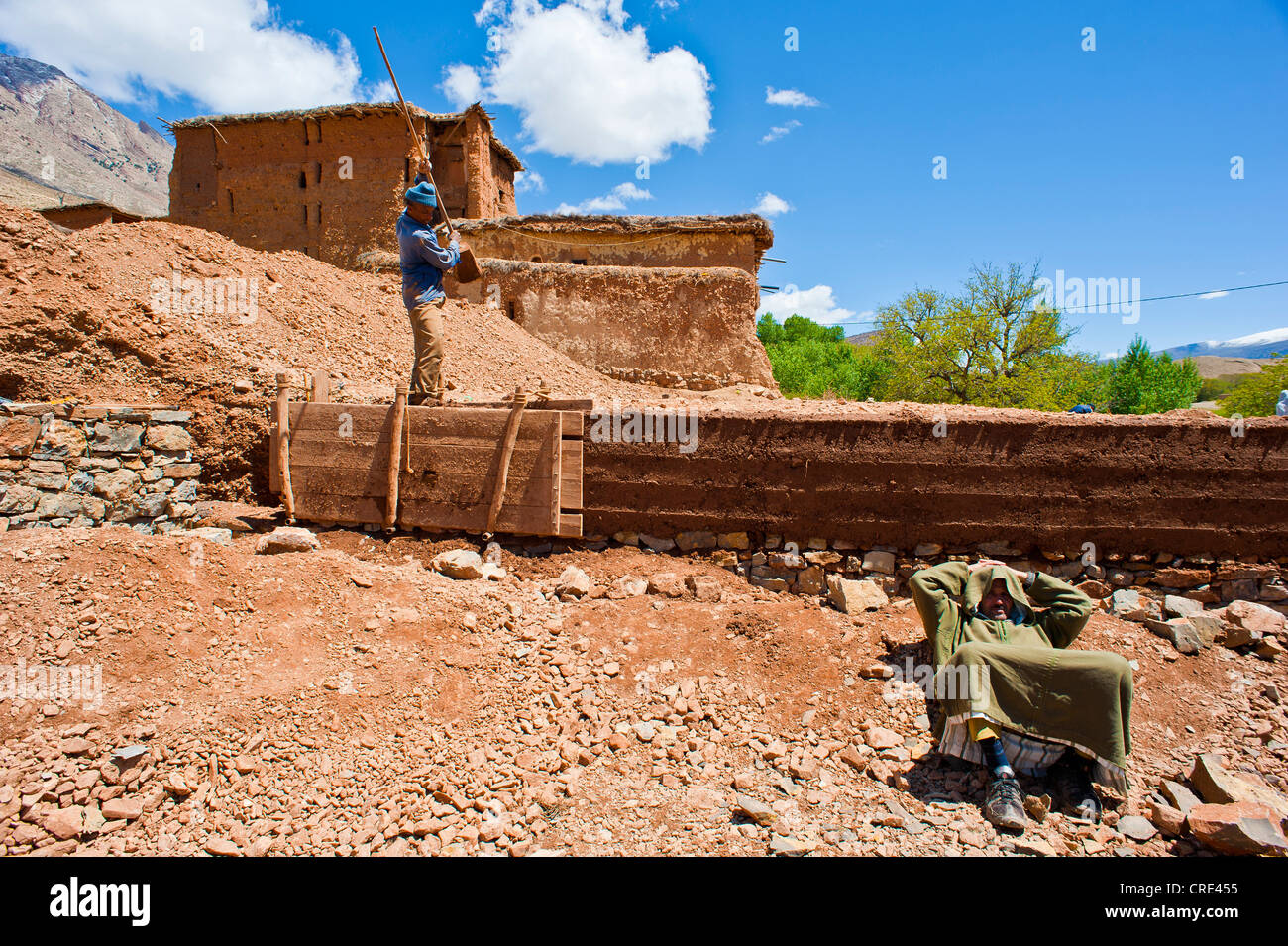 Worker building a rammed-earth wall for a new house, the clay is ...