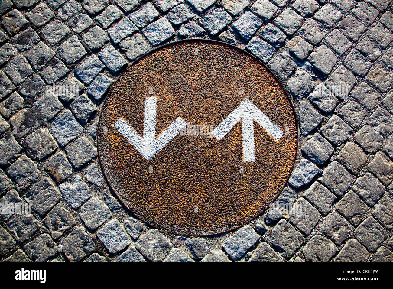 Directional arrows for cyclists on a rusty manhole cover on the ground ...