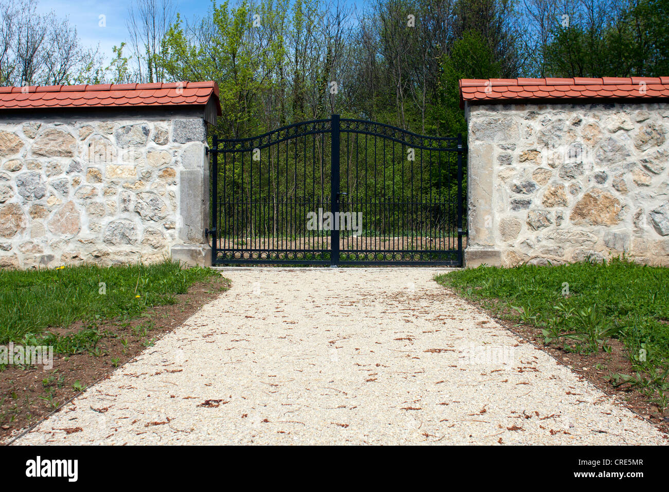 Wall with iron entrance gate and path Stock Photo - Alamy