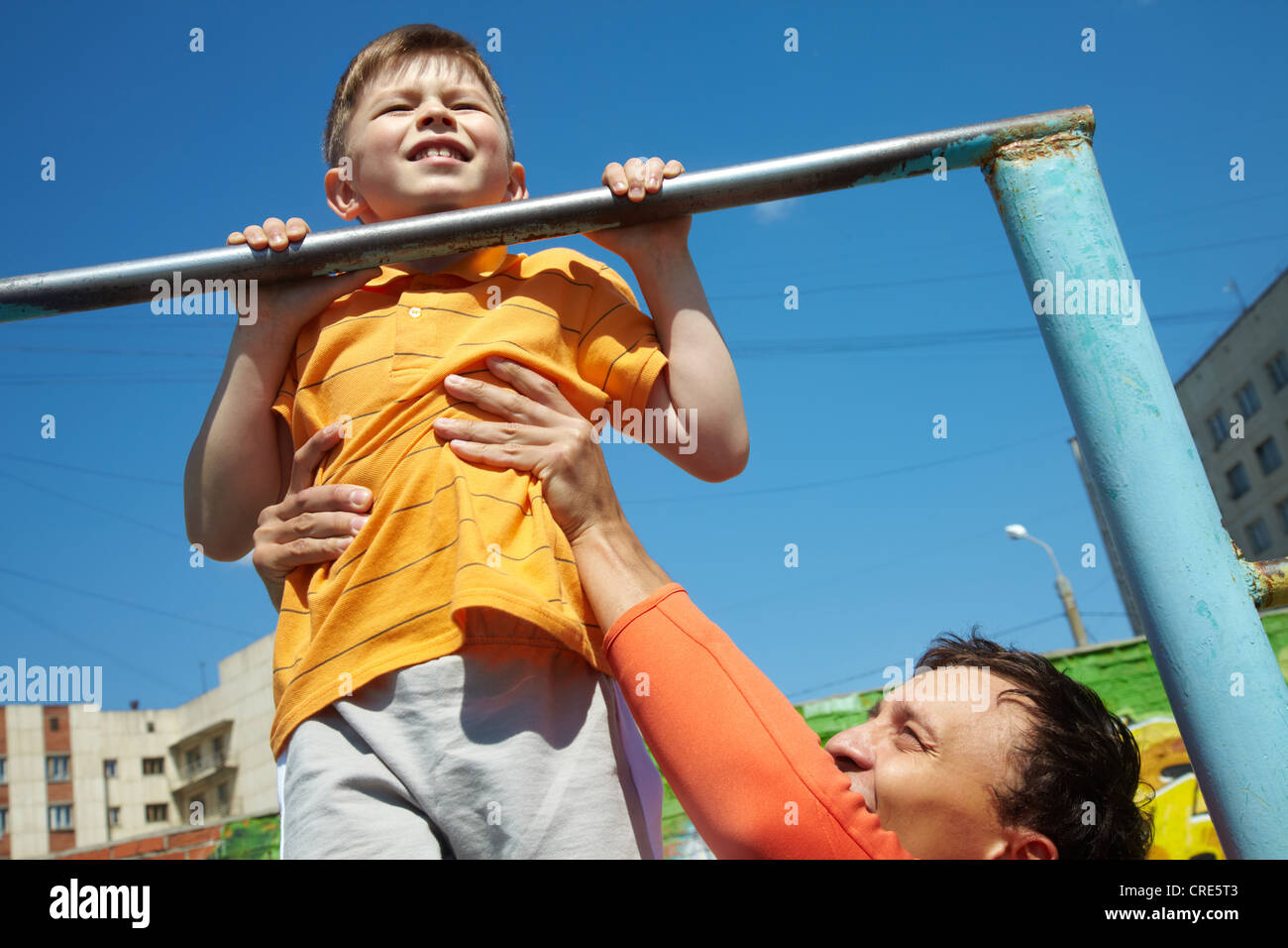 Kid doing chin-ups, his father helping him Stock Photo - Alamy