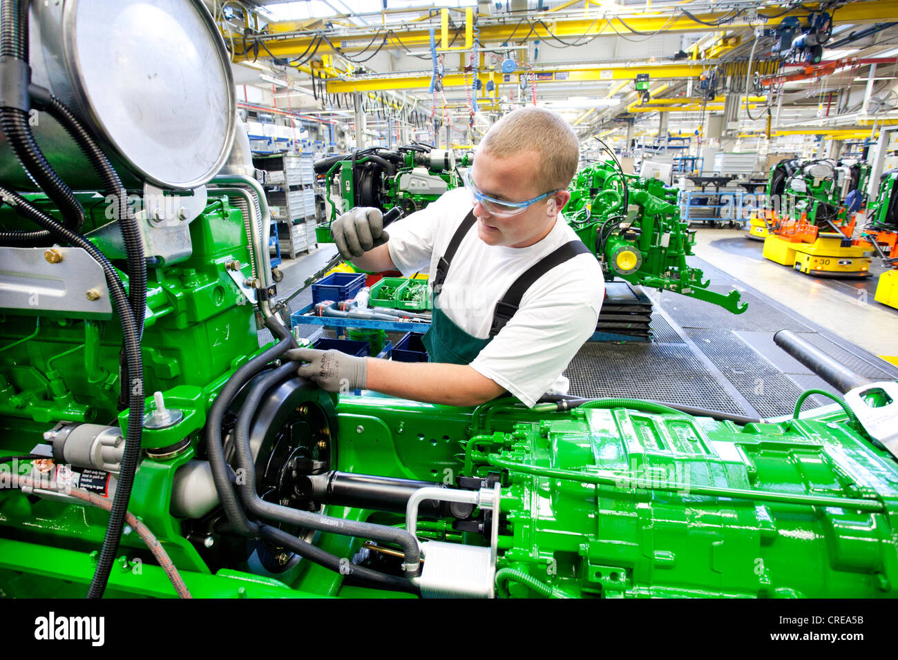Worker is connecting hoses between the engine and the gearbox in the ...