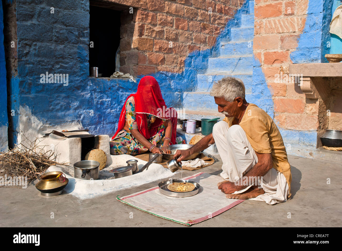 Indian woman with a veil baking chapati flatbread on a small oven in ...