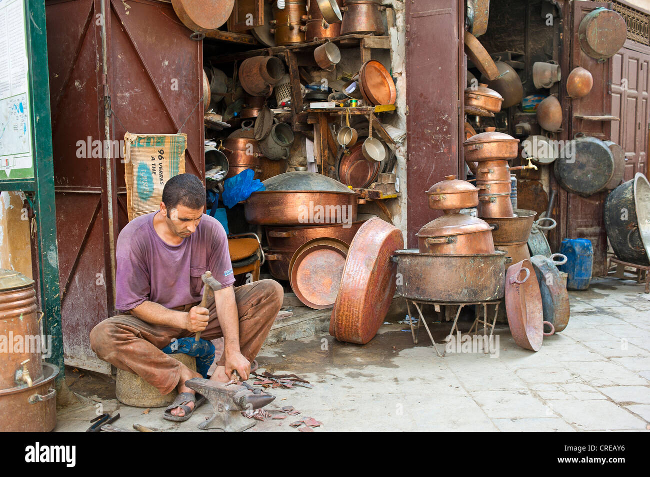 A coppersmith at work outside his shop in the coppersmiths' alley, souk ...