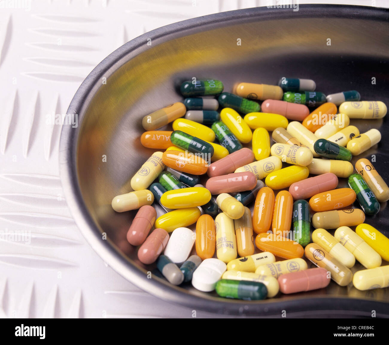 Different colored tablets are in a kidney dish made of stainless steel ...