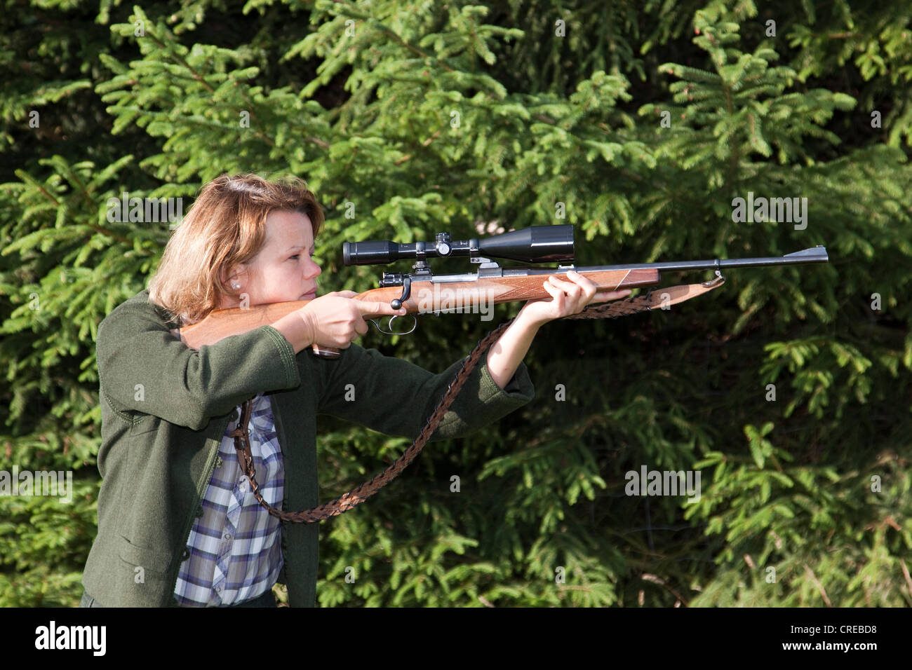 Female hunter in hunting clothes with a levelled rifle, Rhineland ...