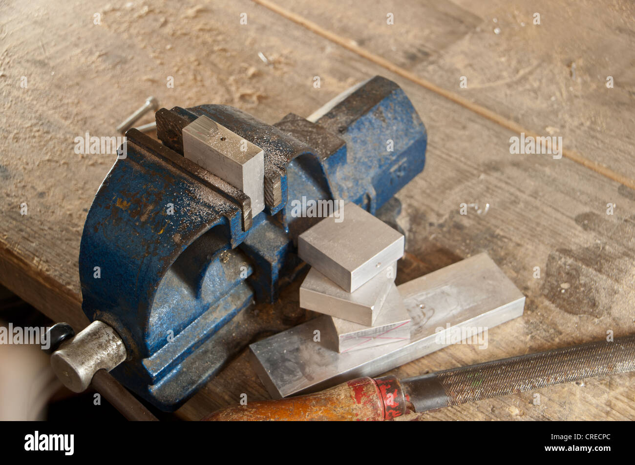 Vice with a block of metal on a wooden workbench Stock Photo - Alamy