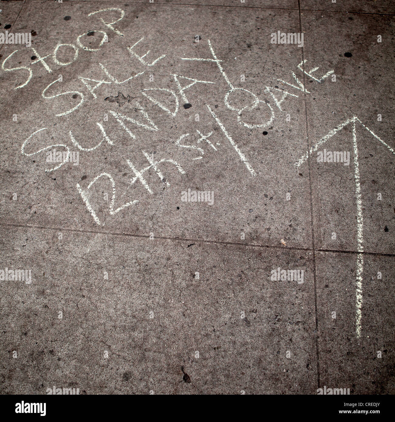 A stoop sale is announced with a chalk message on a sidewalk Stock ...