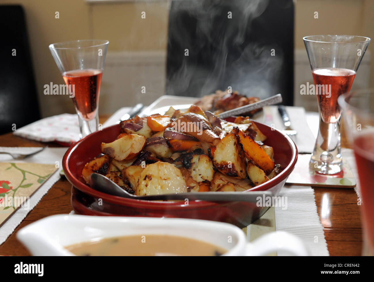 Steaming hot plate of roast vegetables being served up at table for ...