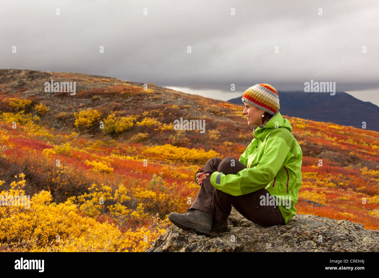 Young woman sitting on a rock, resting, enjoying view, subalpine tundra ...