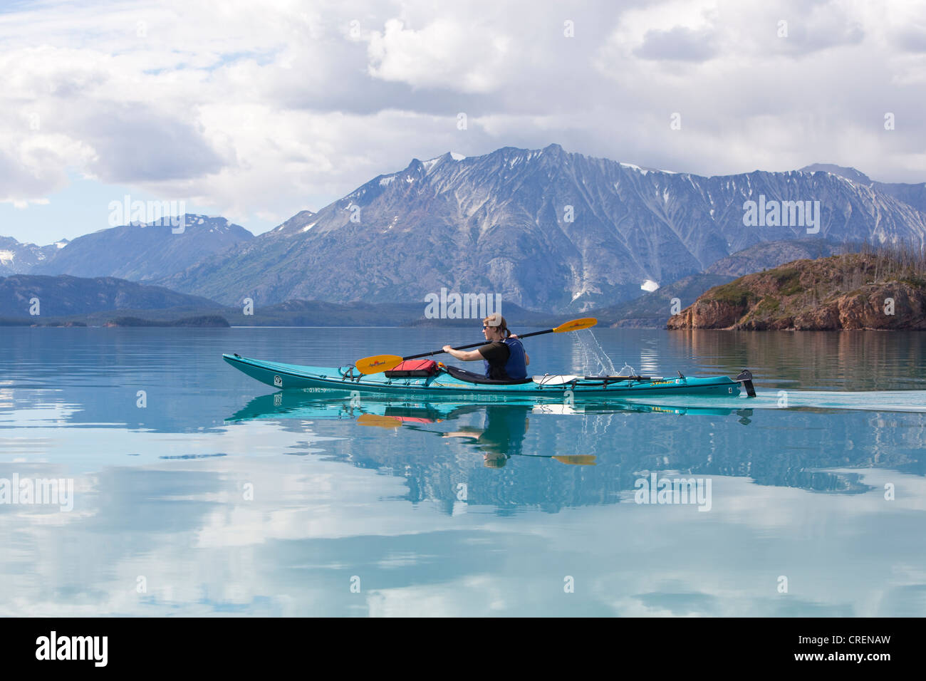 Young woman in a sea kayak, paddling, sea kayaking, mountains behind ...