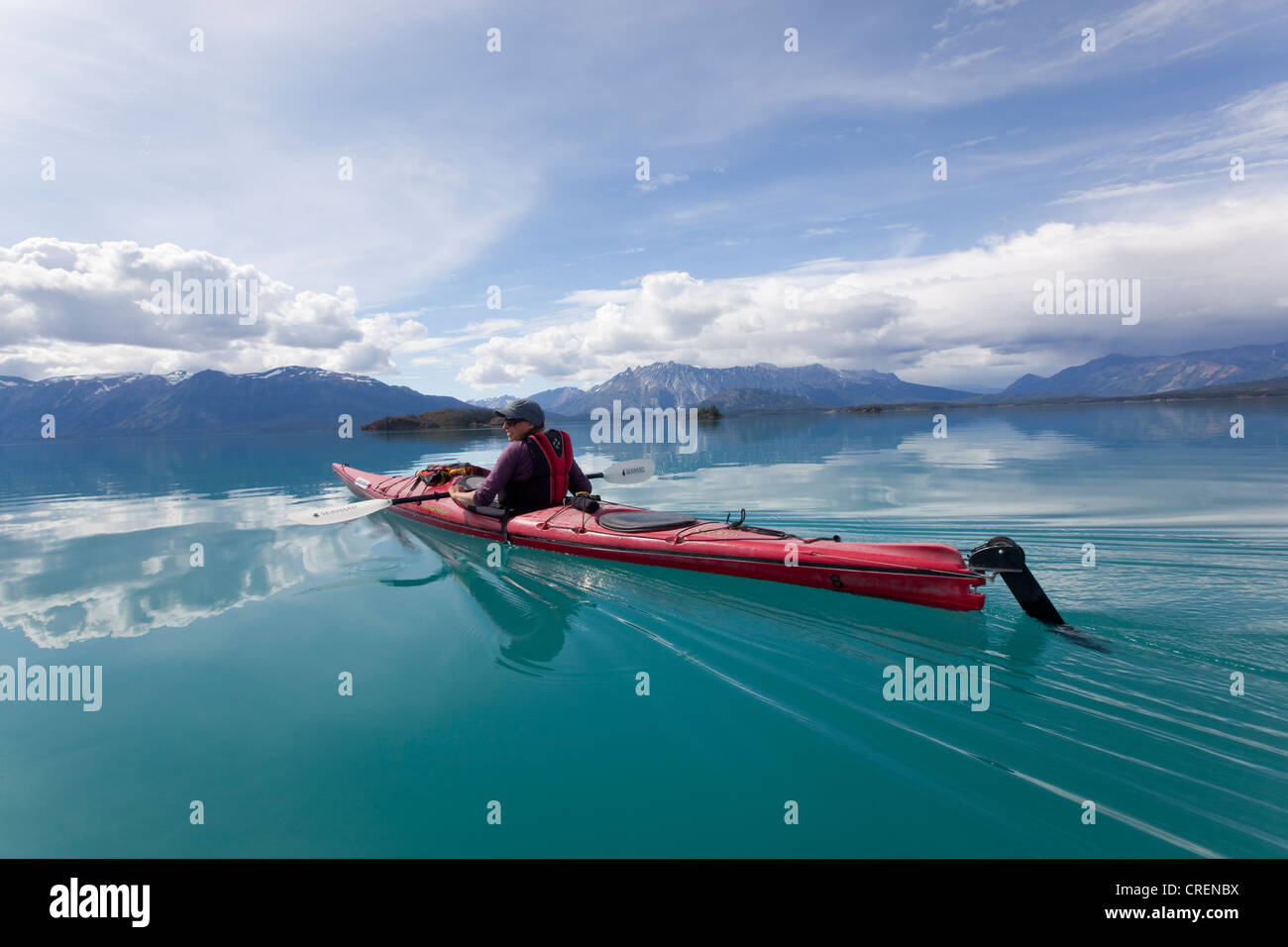 Young woman in a sea kayak, paddling, sea kayaking, mountains behind ...