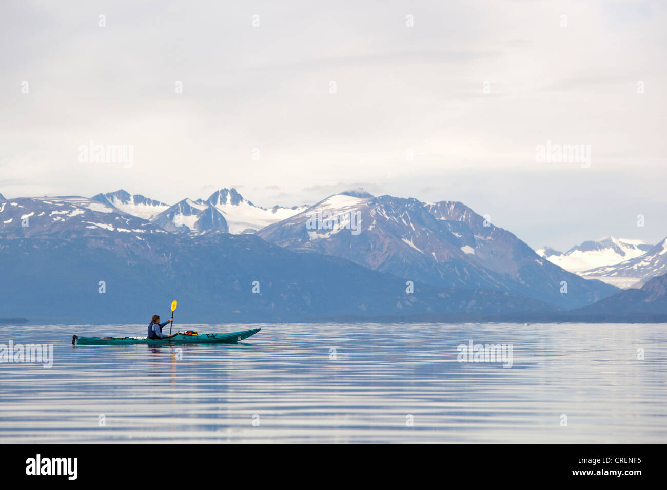 Woman in a sea kayak, paddling, sea kayaking, mountains behind, Tagish ...