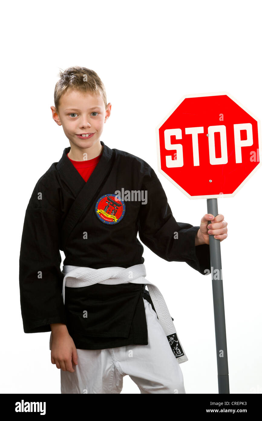 A boy, 9 years, wearing martial arts suit, holding a stop sign, no ...