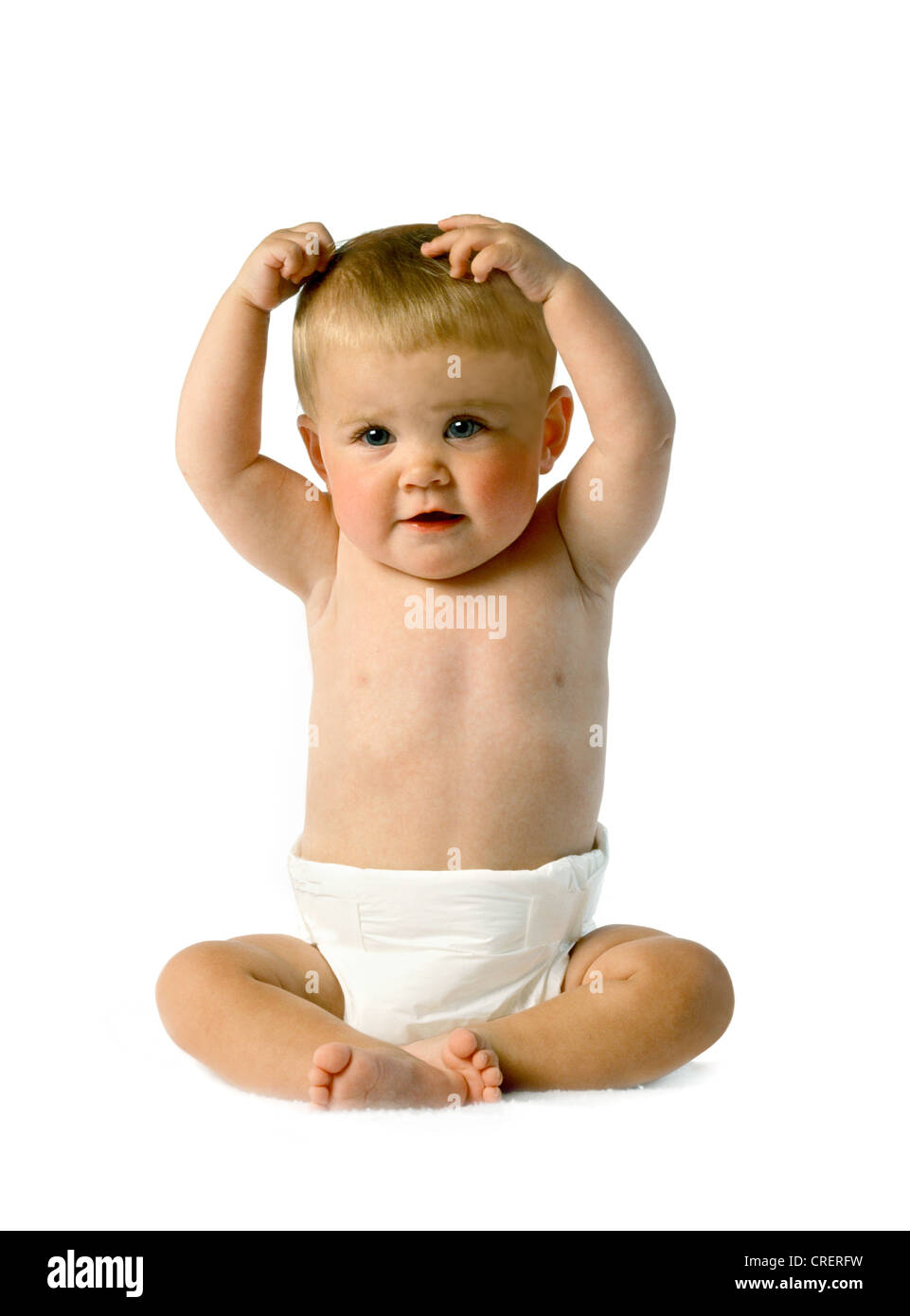 seven month old baby in white nappy, sitting upright with hands on head ...