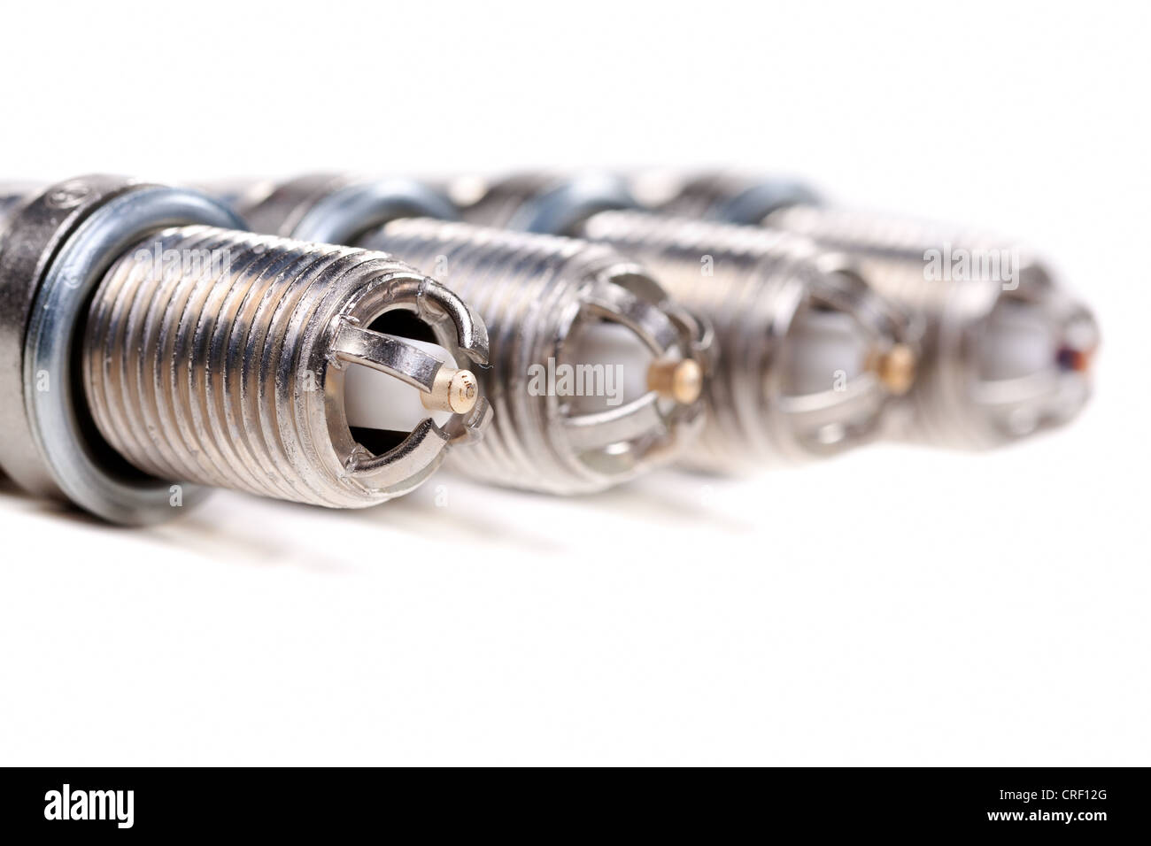 Set of four platinum spark plugs on a white background. Shallow depth ...