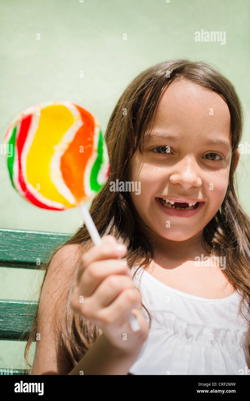 Portrait of cute little girl with candy smiling and looking at camera ...
