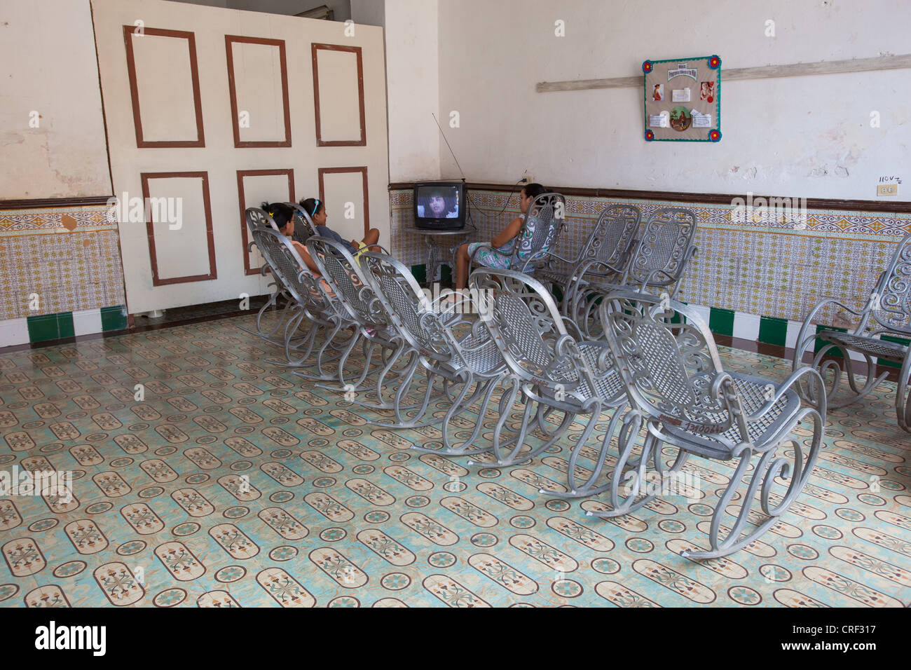 Women sitting in wrought iron rocking chairs watching TV in Trinidad ...