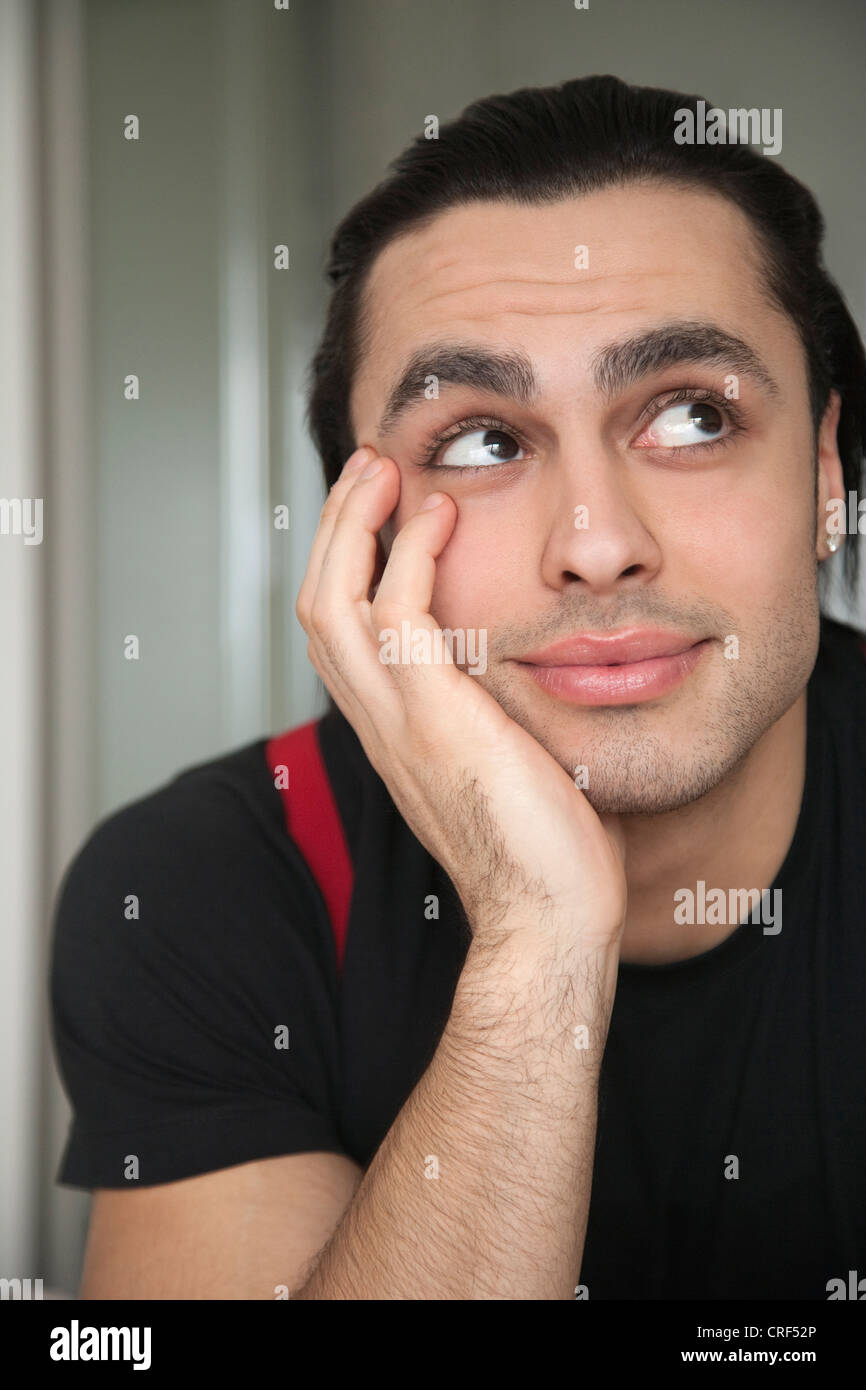 Smiling young man looking up with curiosity Stock Photo - Alamy