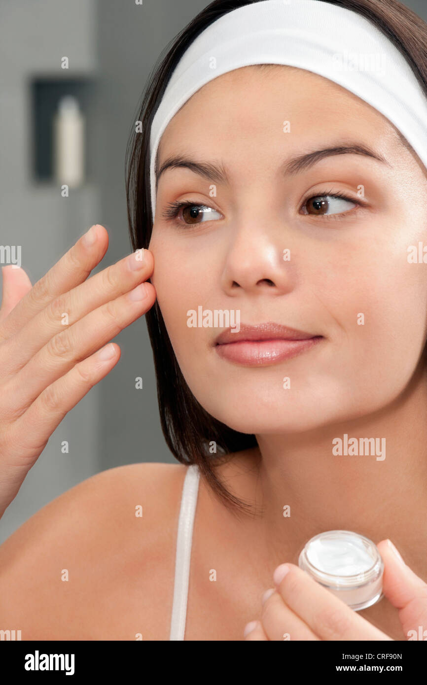 Woman applying moisturizer in mirror Stock Photo - Alamy
