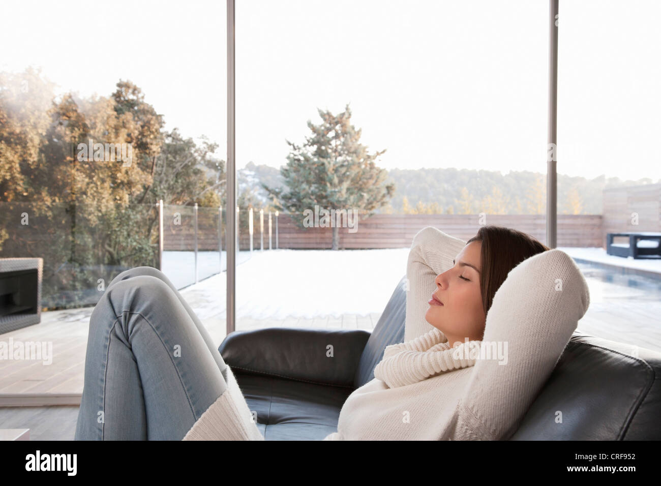 Woman relaxing on sofa in living room Stock Photo - Alamy