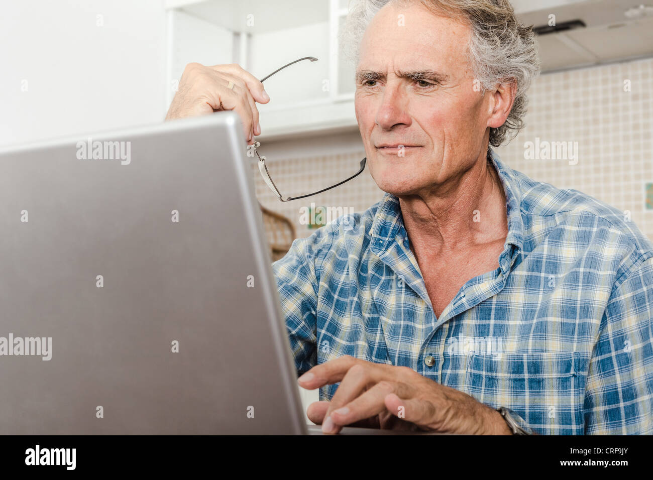 Older man using laptop in kitchen Stock Photo - Alamy