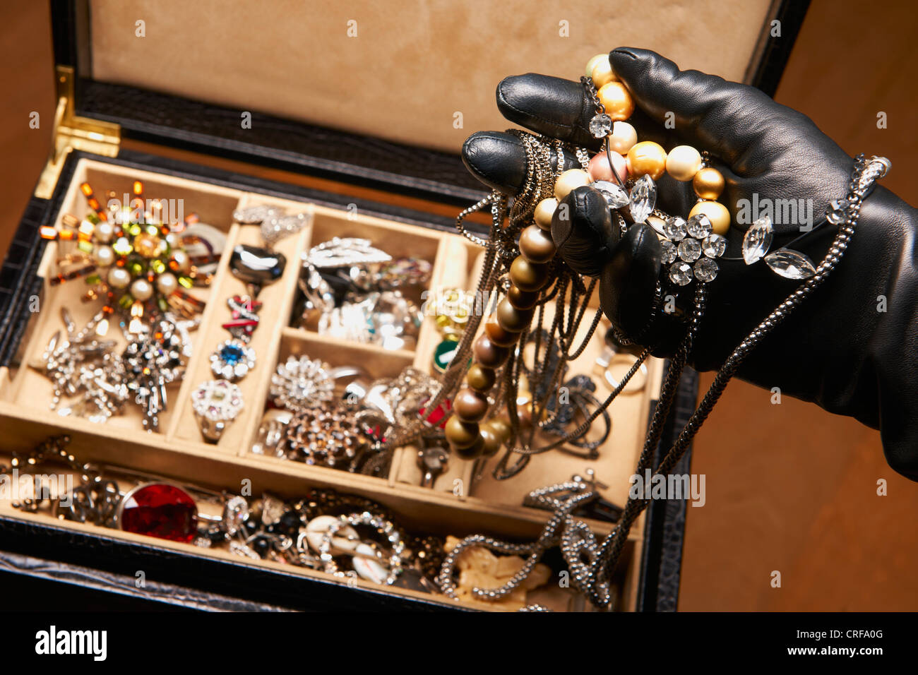 Gloved hand stealing jewelry Stock Photo - Alamy