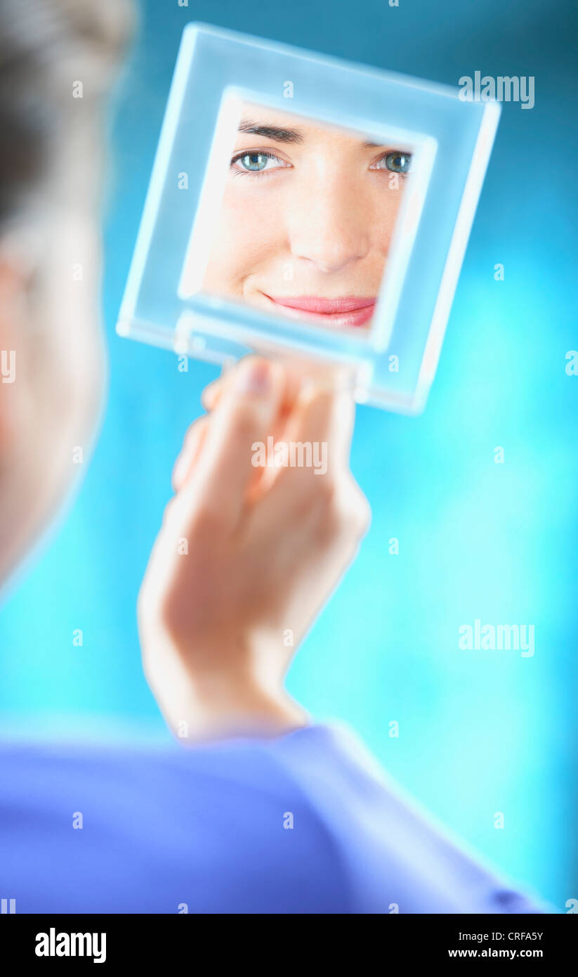 Woman examining herself in mirror Stock Photo - Alamy