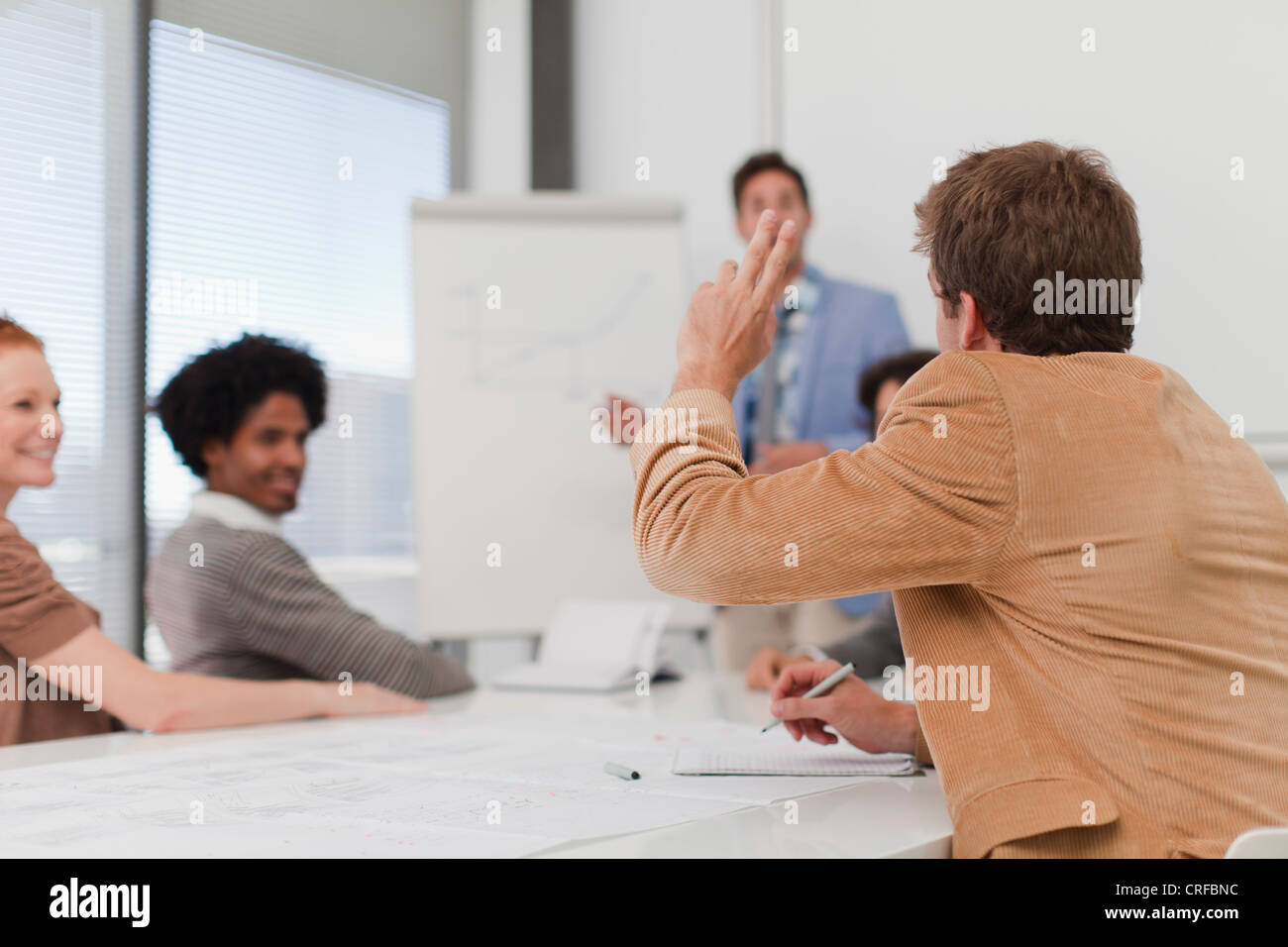 Businessman raising hand in meeting Stock Photo - Alamy