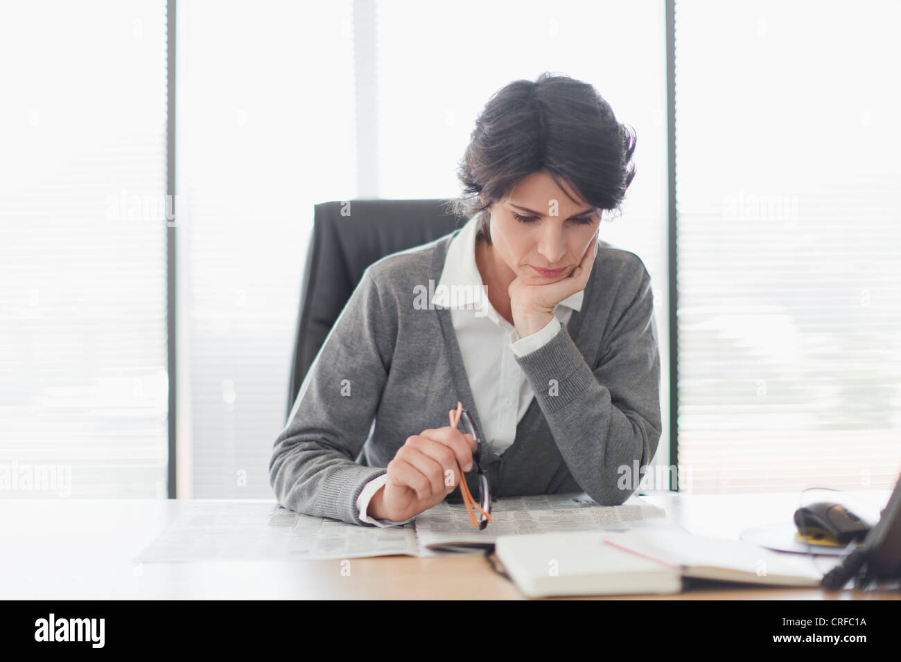 Businesswoman reading newspaper at desk Stock Photo - Alamy
