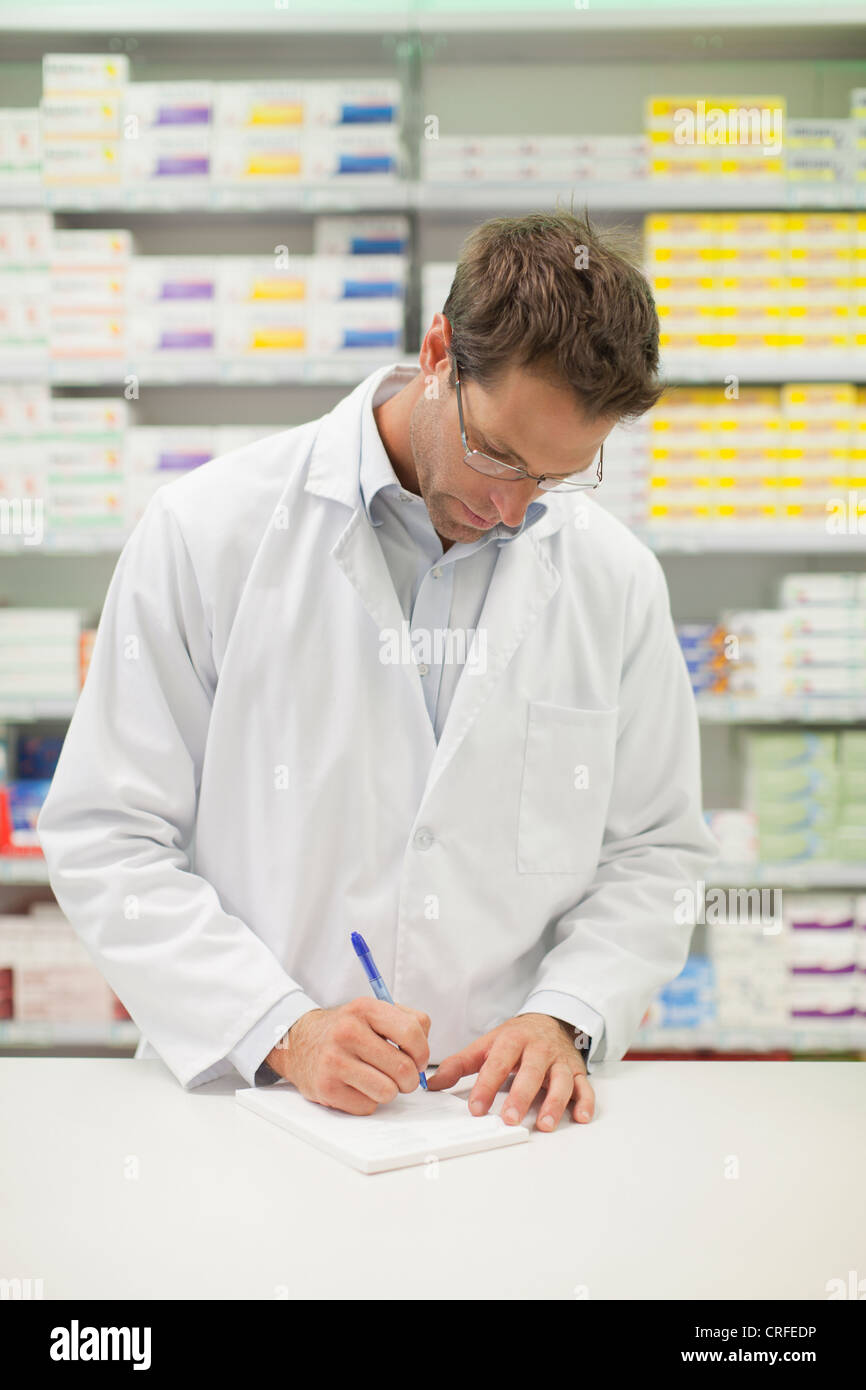 Pharmacist making notes at counter Stock Photo - Alamy