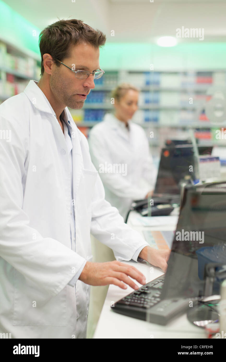 Pharmacist using computer at counter Stock Photo - Alamy